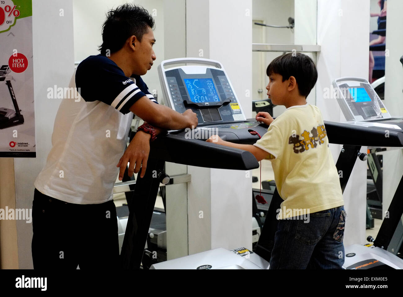 young boy trying out an exercise machine in a store in a shopping mall ...