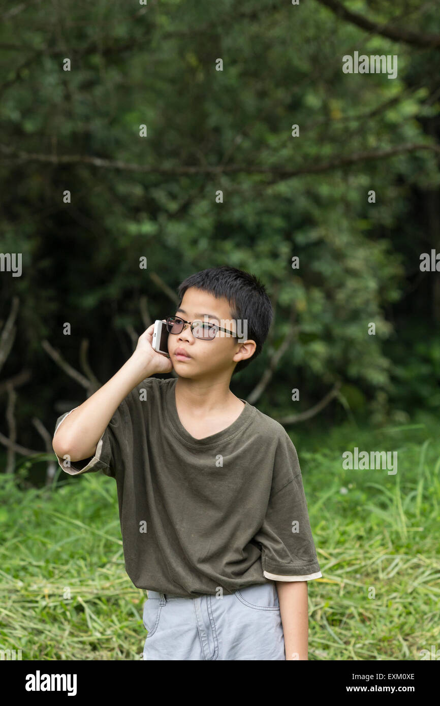 Asian Thai young boy talking on mobile phone outdoor Stock Photo - Alamy
