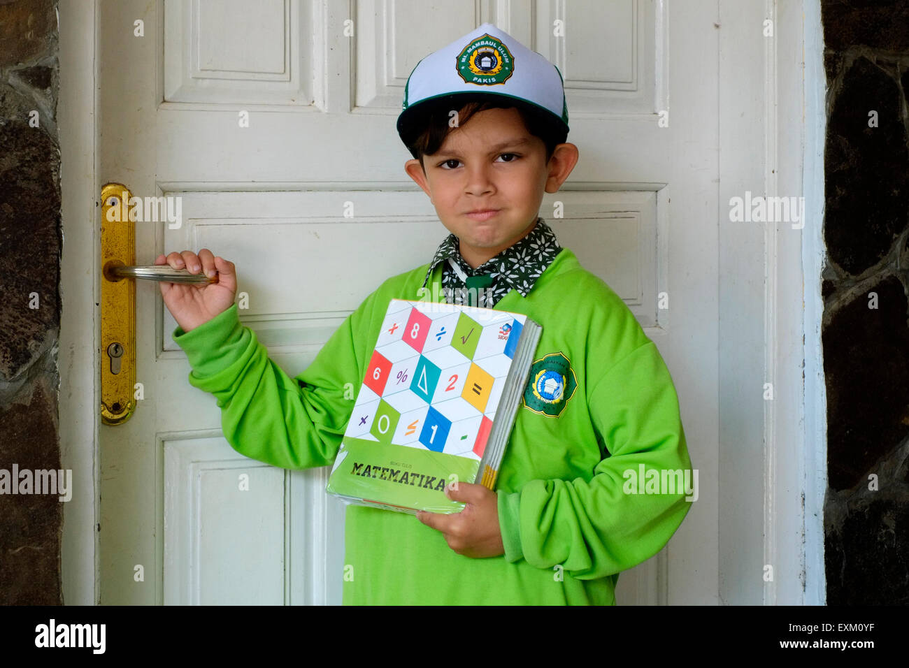 little boy dressed in his school uniform arrives home carrying his ...