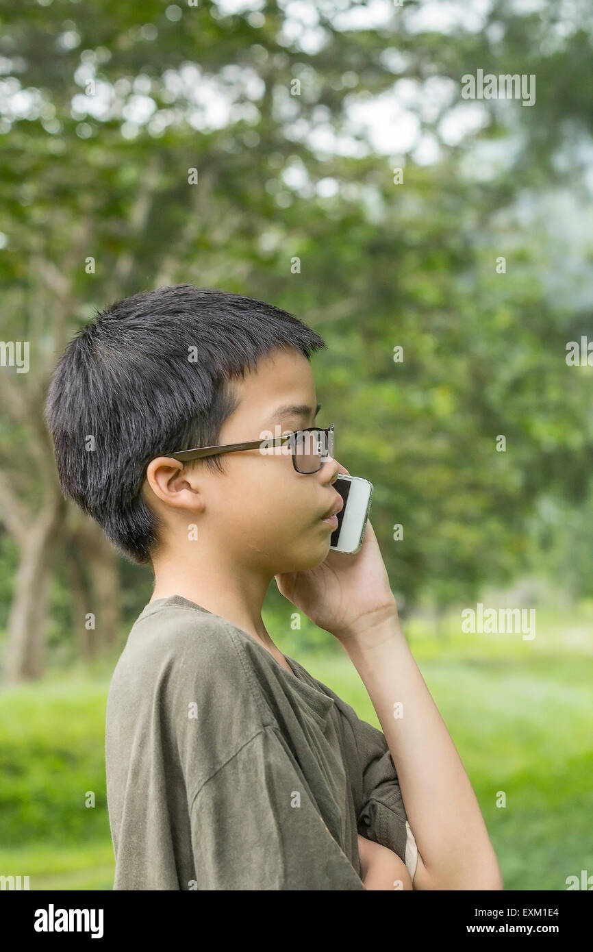Asian Thai young boy talking on mobile phone outdoor Stock Photo - Alamy