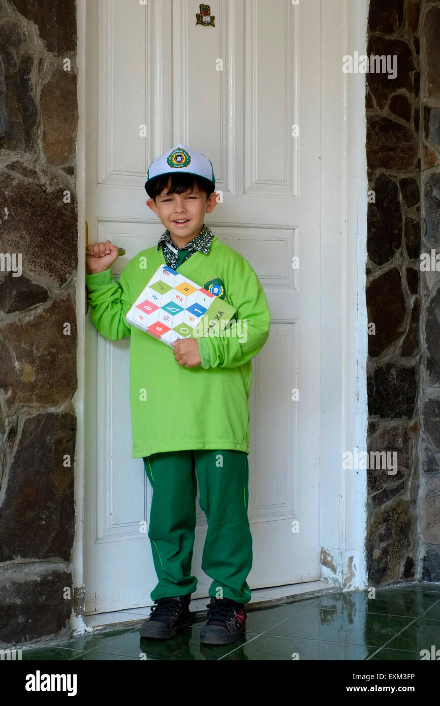 little boy dressed in his school uniform arrives home carrying his ...