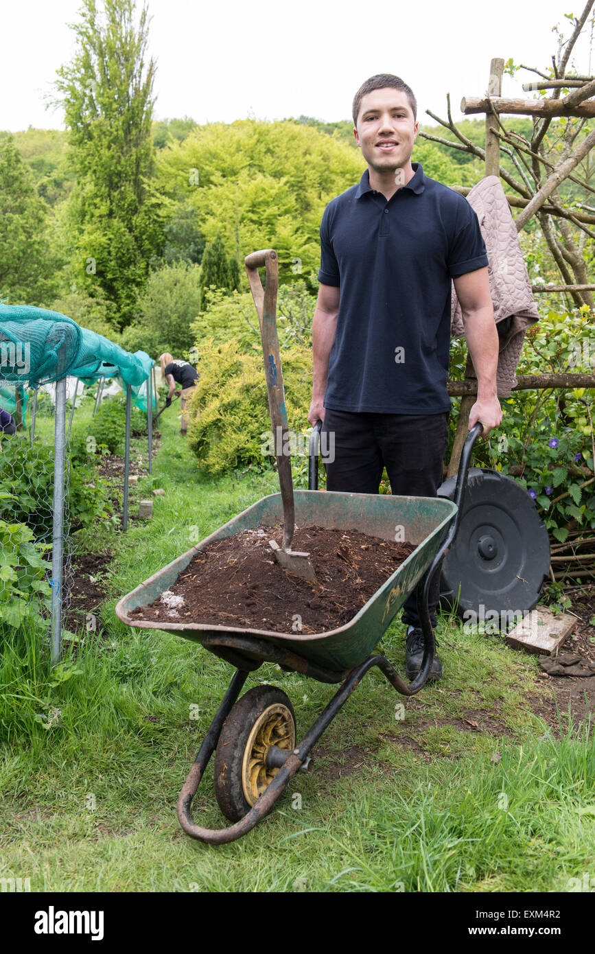 office workers doing some voluntary gardening work with wheel barrows ...