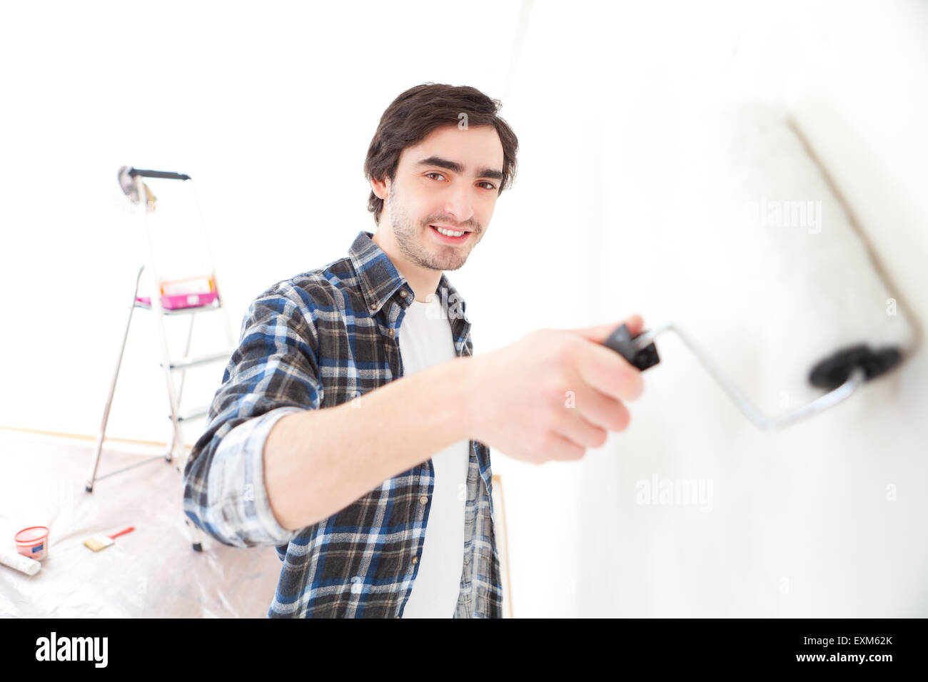 View of an attractive young man painting a wall in his new flat Stock ...