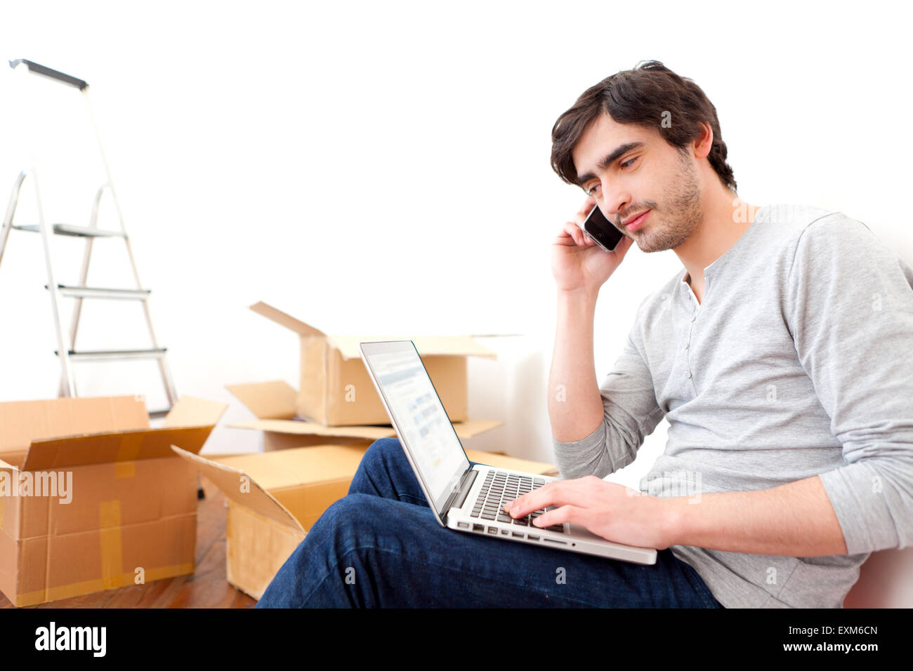 View of a Handsome young man in his new flat ordering on his laptop ...