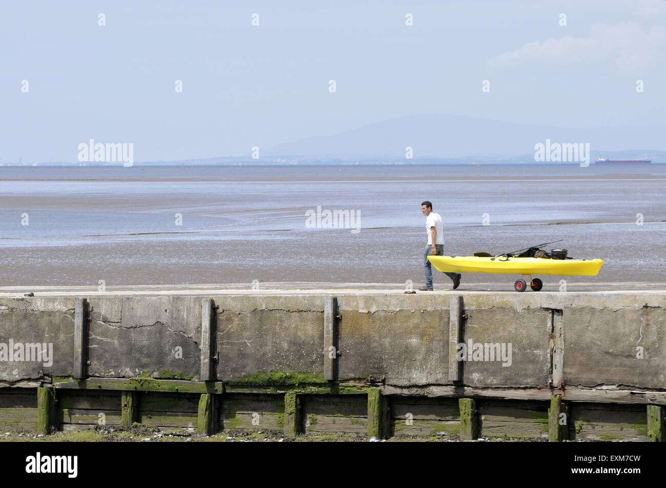 Man pulling canoe on wheels down launch ramp at Knott-End-on-Sea Stock ...