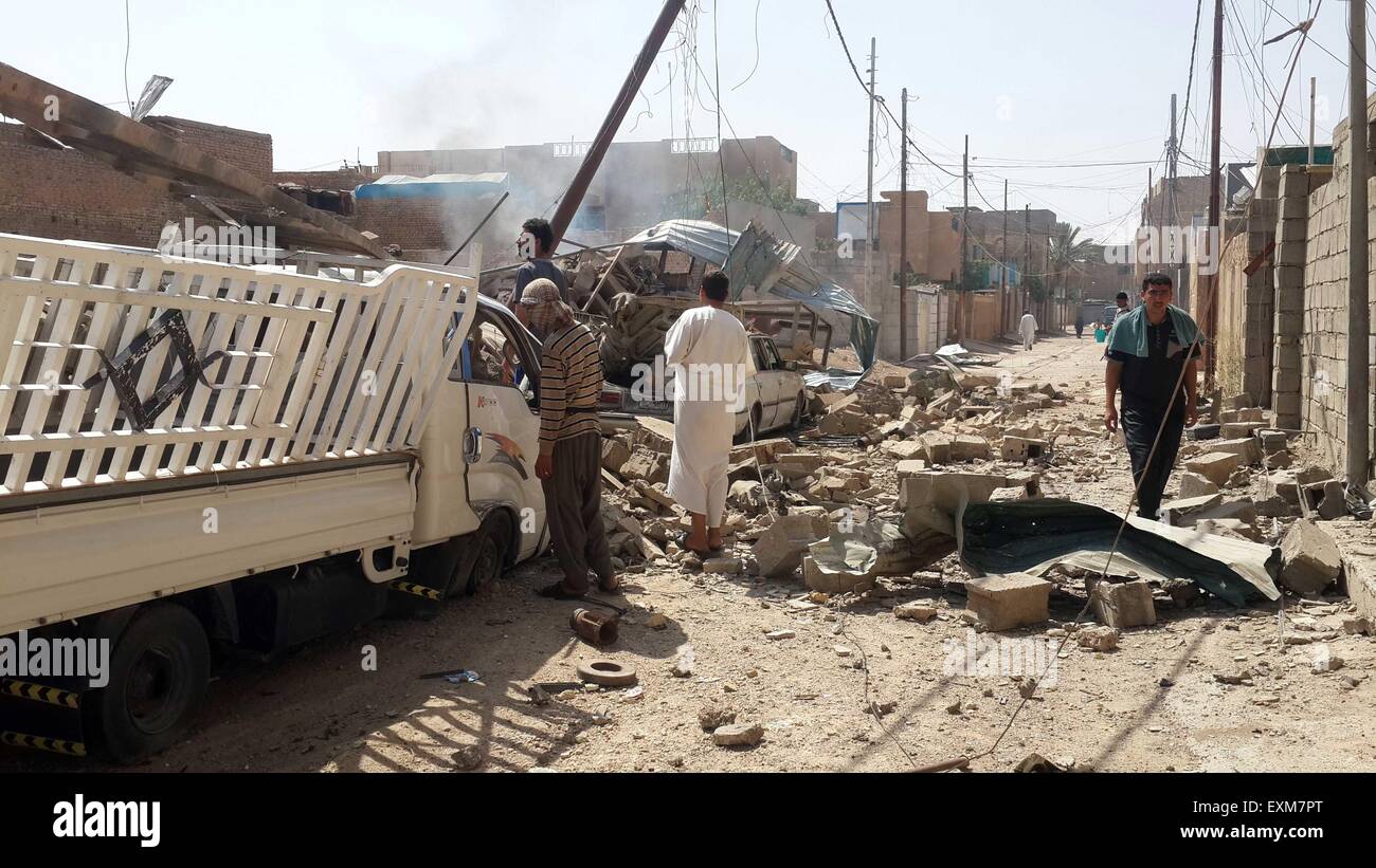 Fallujah, Iraq. 15th July, 2015. People gather around destroyed cars ...