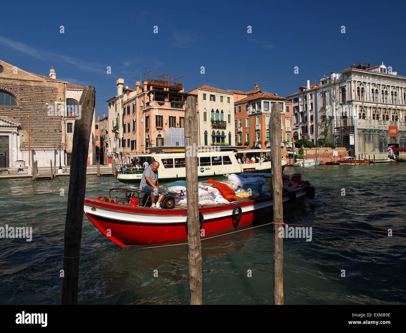 Man in a red boat sailing throught the Grand Canal in Venice, Italy ...