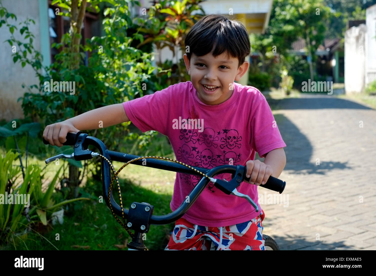 seven year old little boy playing on his bicycle in a village street in ...