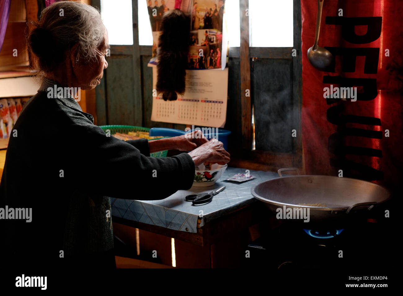elderly lady cooking a rice dish in a simple basic kitchen in a rural ...