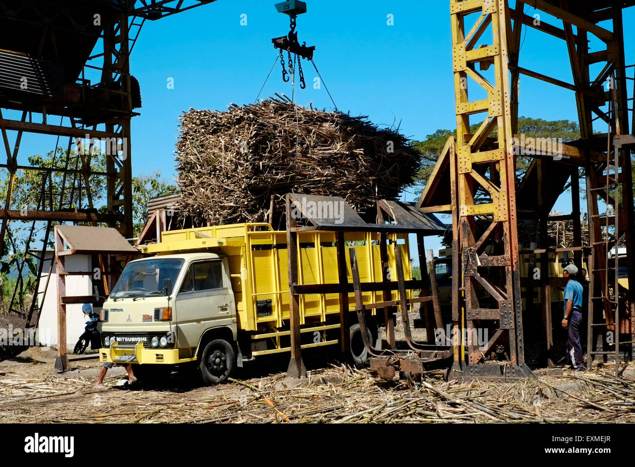 workers at a busy sugar cane processing factory using trucks and trains ...