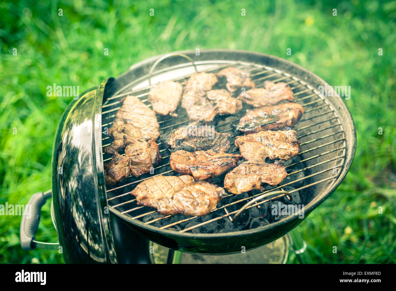 Grilling pork meat with barbecue stuff. Horizontal filtered close up ...