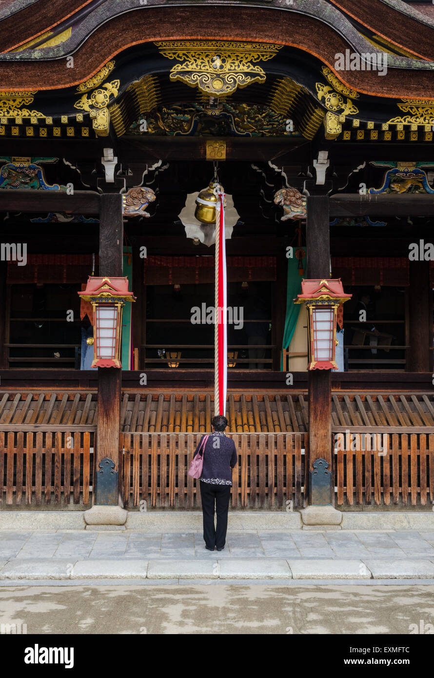 Woman praying in front of the main shrine at the Kitano Tenmangu Shrine ...