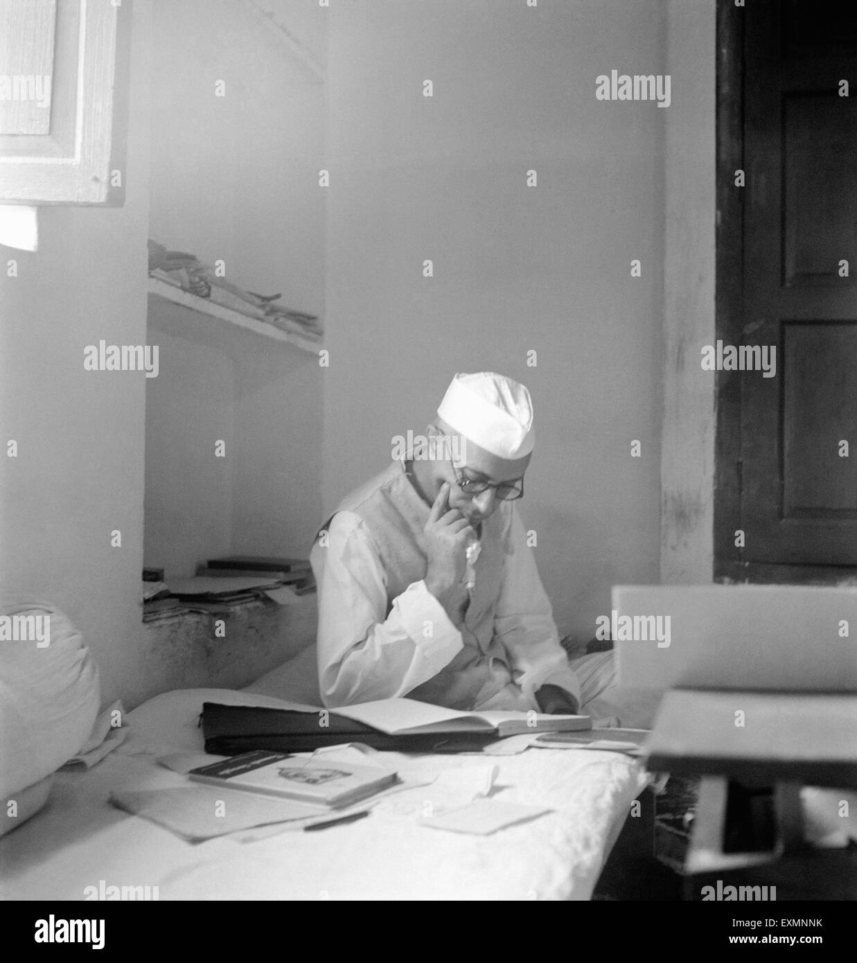 Jawaharlal Nehru reading a note by Mahatma Gandhi in room at Bhangi ...