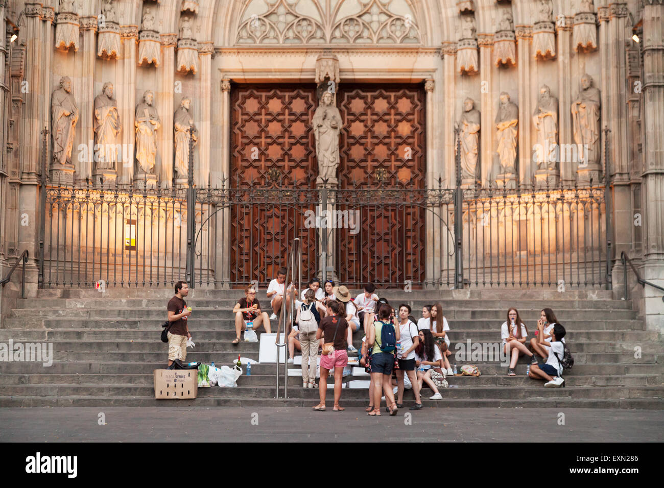 Teenagers on a school trip sitting on the steps of Barcelona Cathedral ...