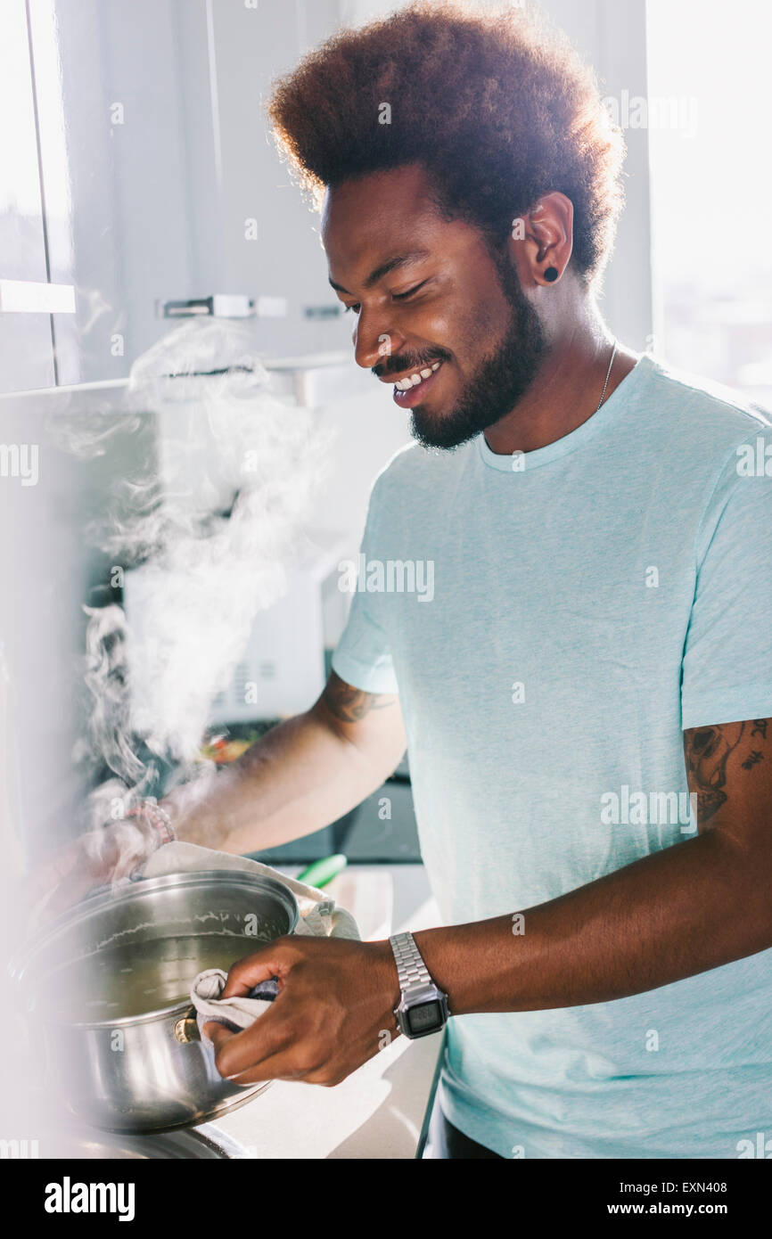 Smiling man holding cooking pot with hot water Stock Photo - Alamy