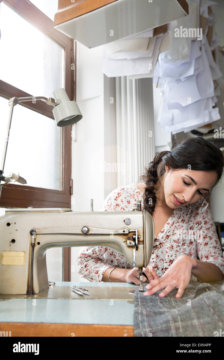 Young seamstress with sewing machine in manufacturer's workshop Stock ...