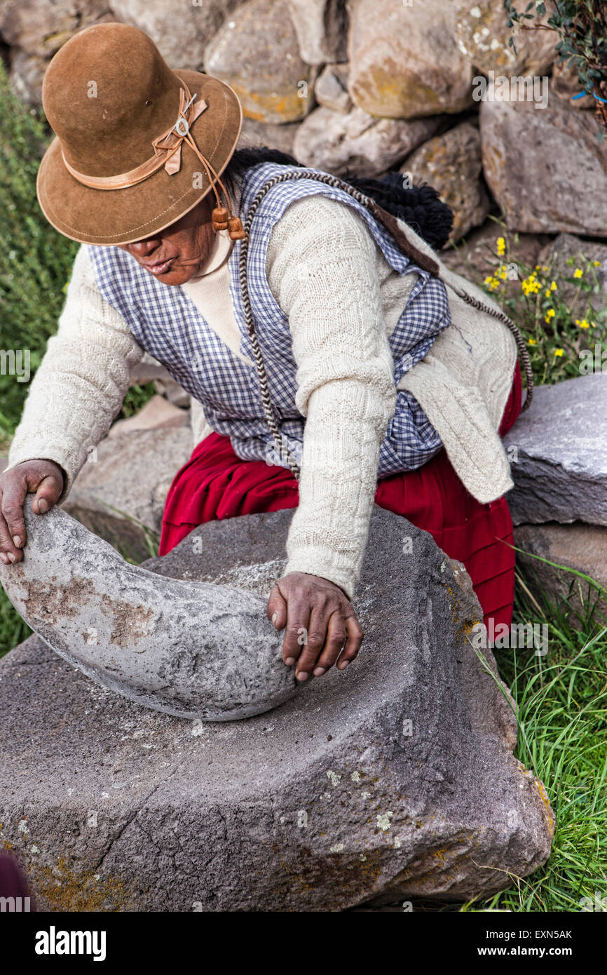 Older traditional Peruvian farm woman demonstrates how to grind ...