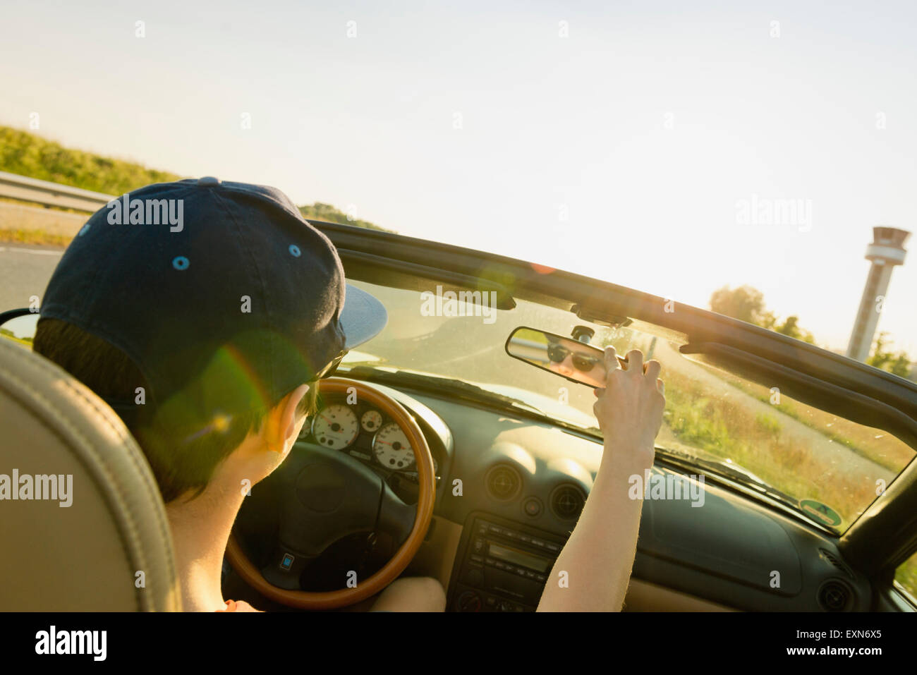 Teenager driving in a convertible car adjusting rear view mirror Stock ...