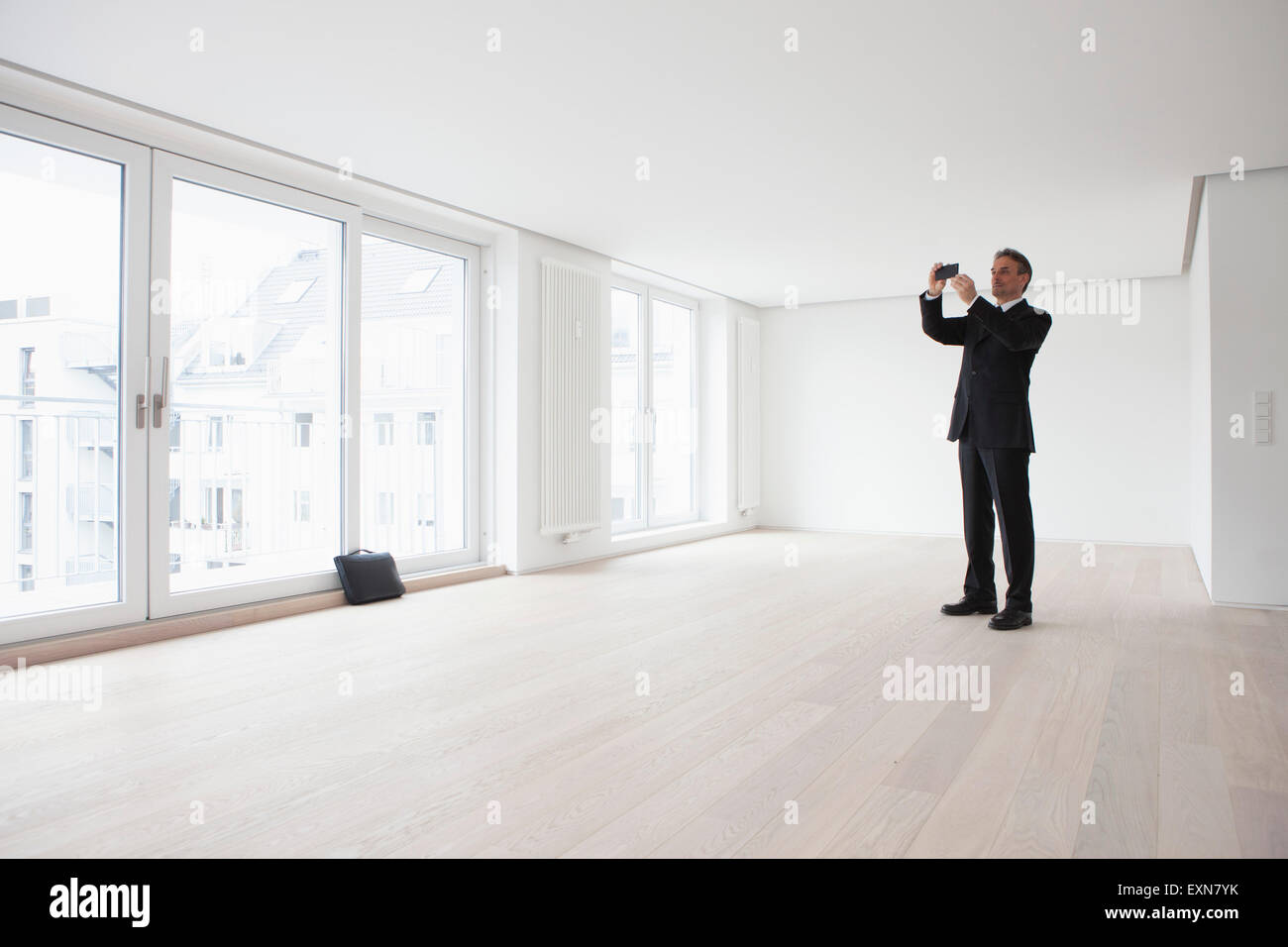 Estate agent standing in empty apartement, taking pictures Stock Photo ...