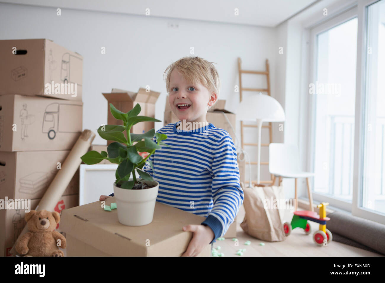 Little blond boy helping with cardboard boxes Stock Photo - Alamy