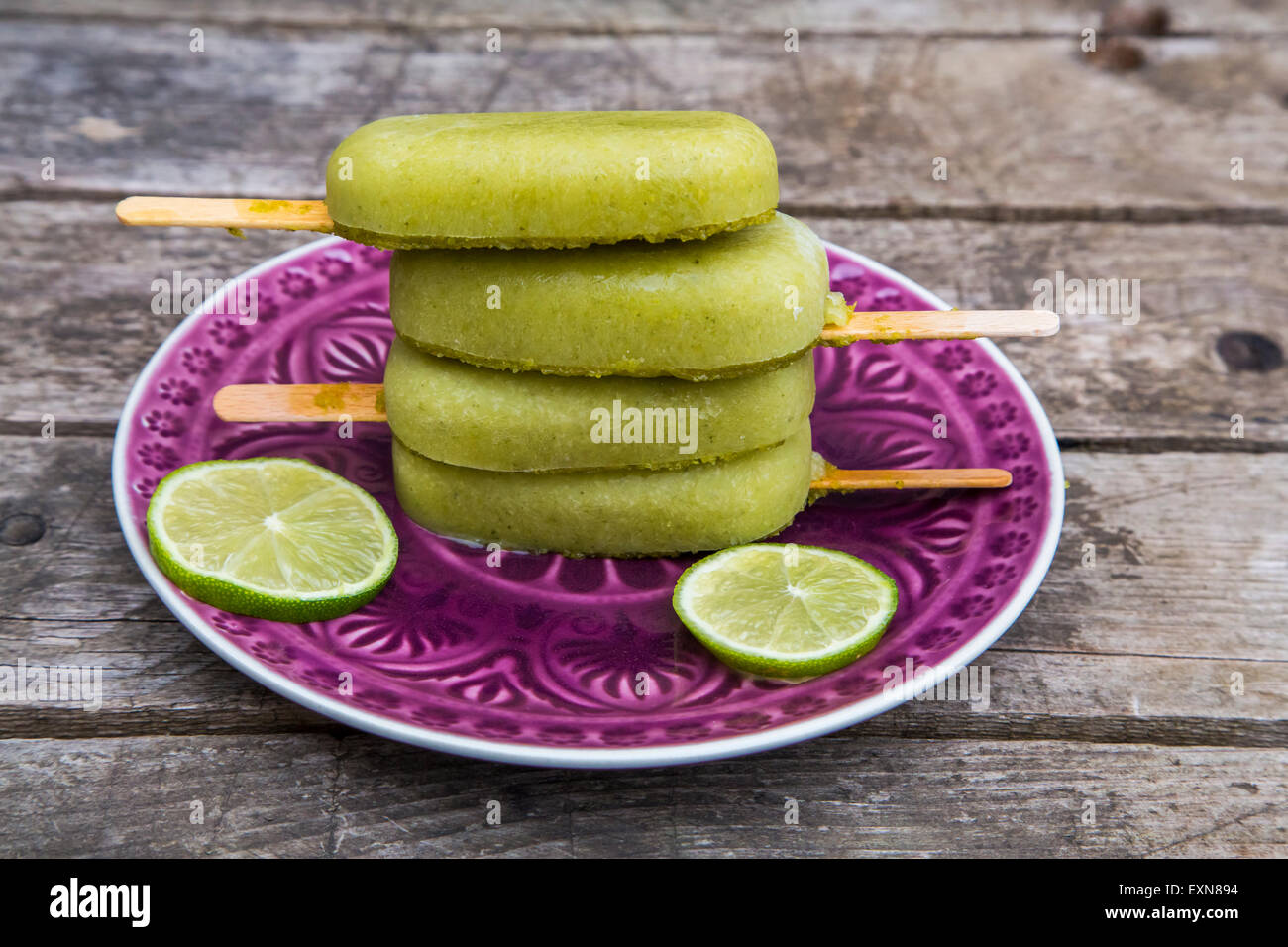 Stack of avocado ice lollies and slices of lime on plate Stock Photo ...