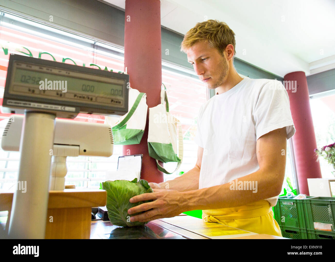 Male shop assistant in wholefood shop, weighing gabbage Stock Photo - Alamy