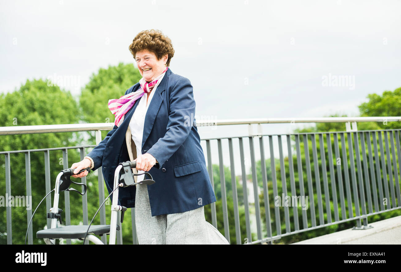 Smiling senior woman walking with wheeled walker Stock Photo - Alamy