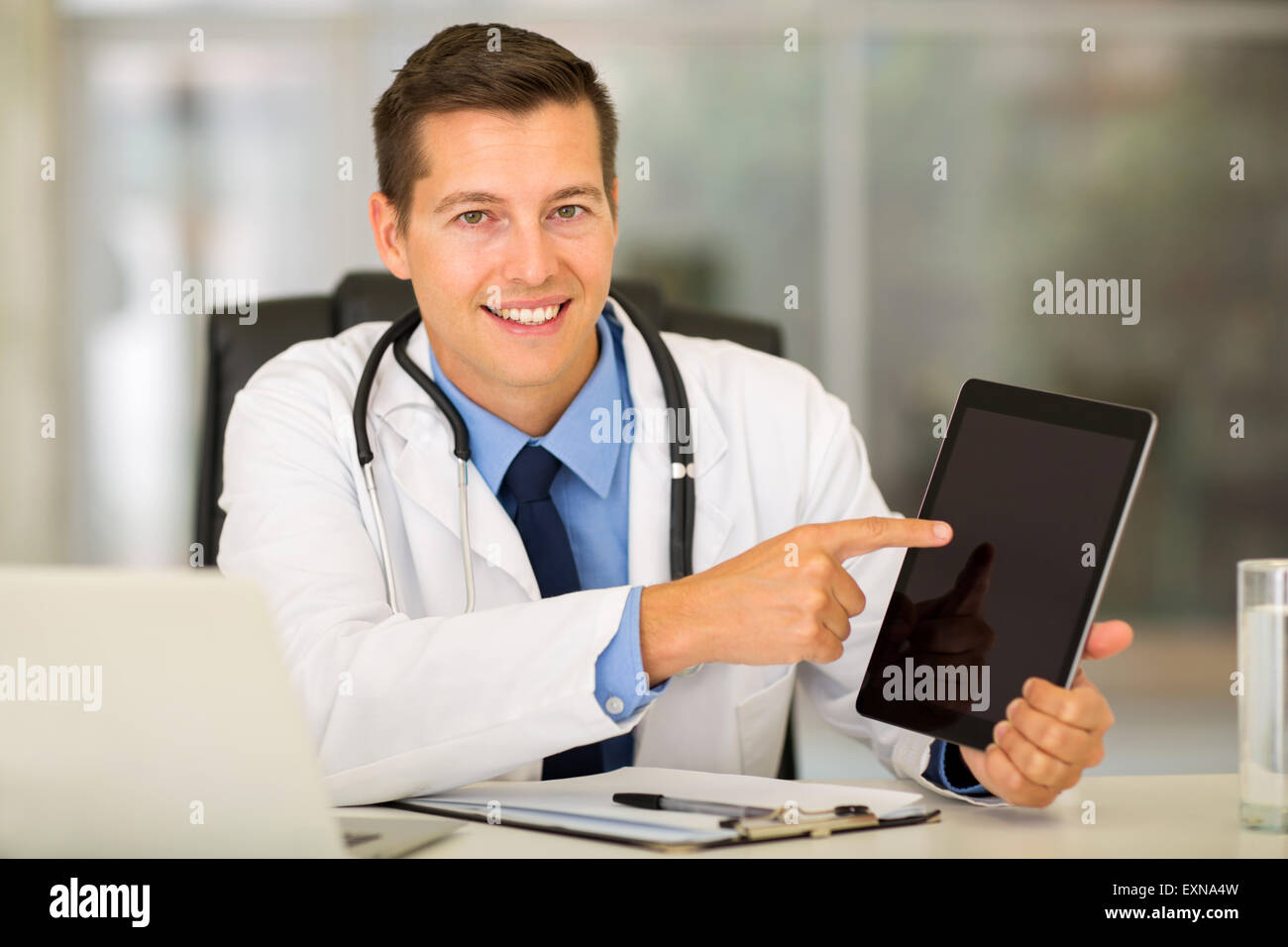 friendly young doctor pointing tablet computer Stock Photo - Alamy