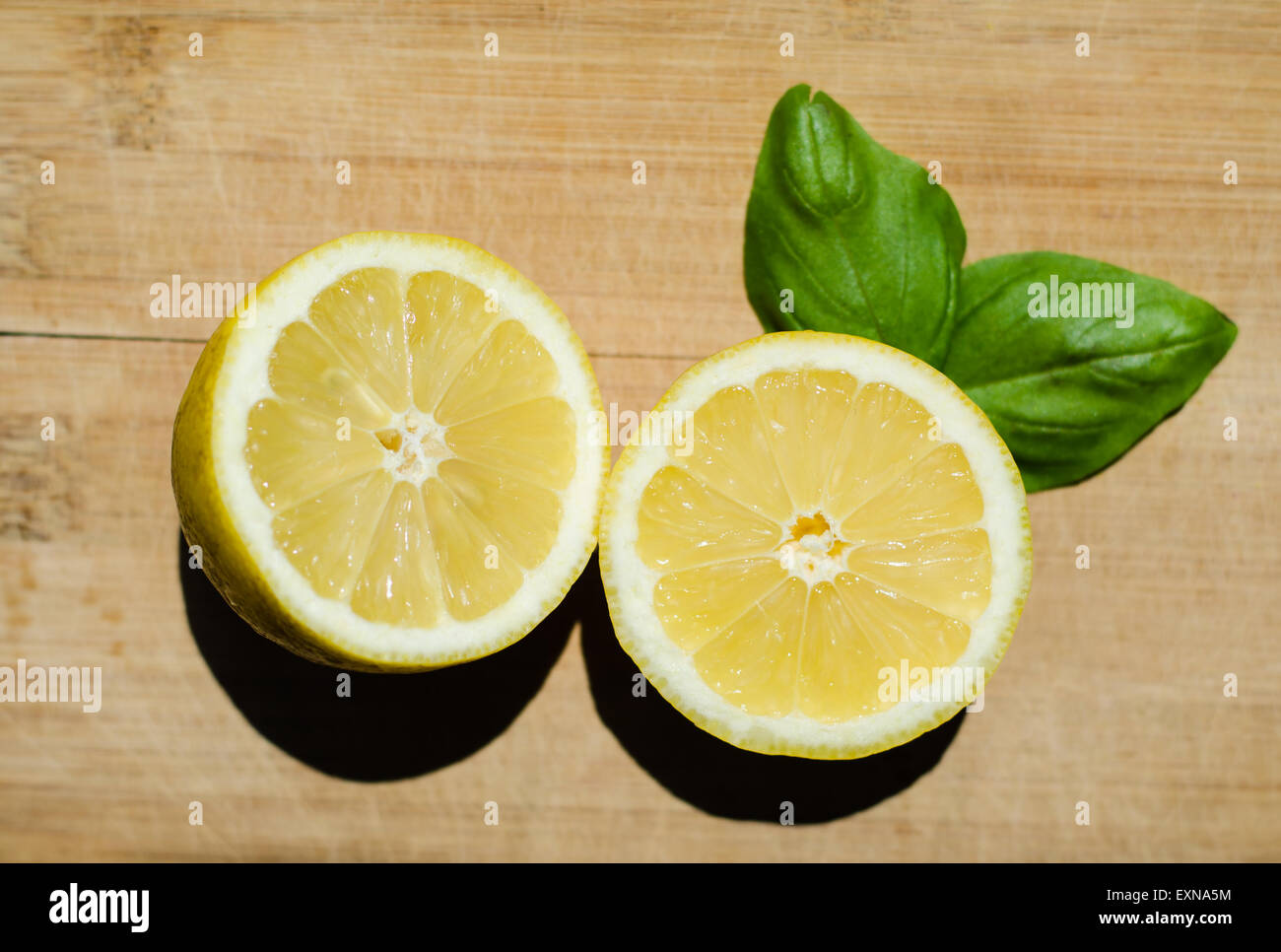 cut lemon with basil leafs on a wooden desk Stock Photo - Alamy