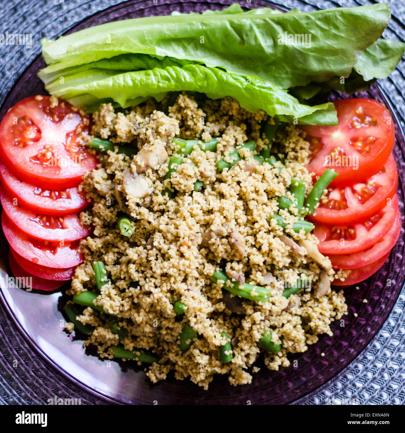 A plate of couscous with basil and spices served with tomato slices and ...
