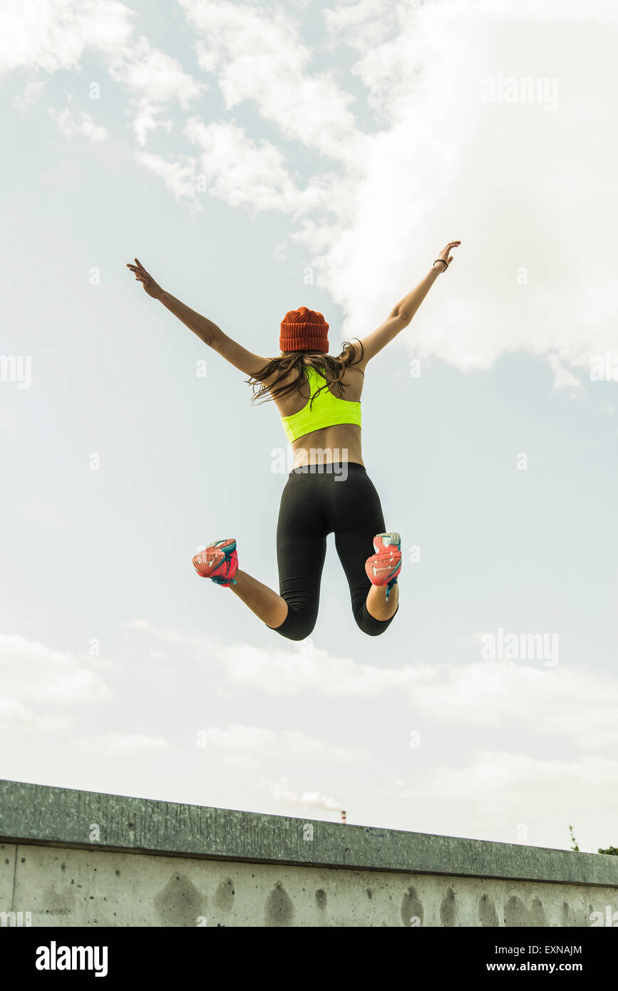 Back view of young woman jumping in the air Stock Photo - Alamy