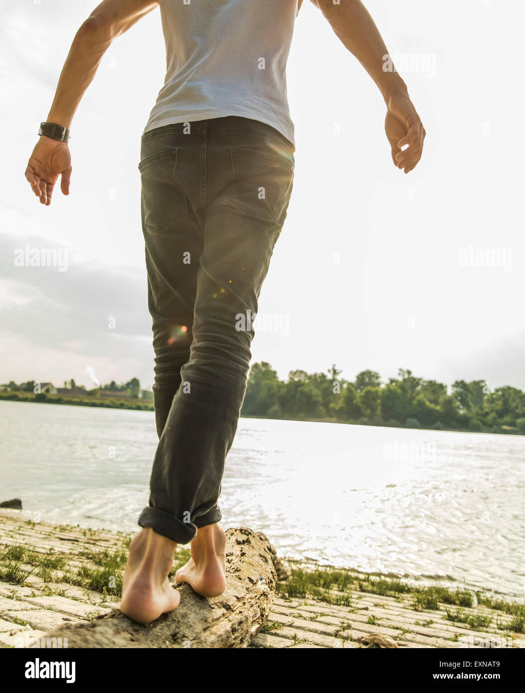 Young man balancing on log by the riverside Stock Photo - Alamy