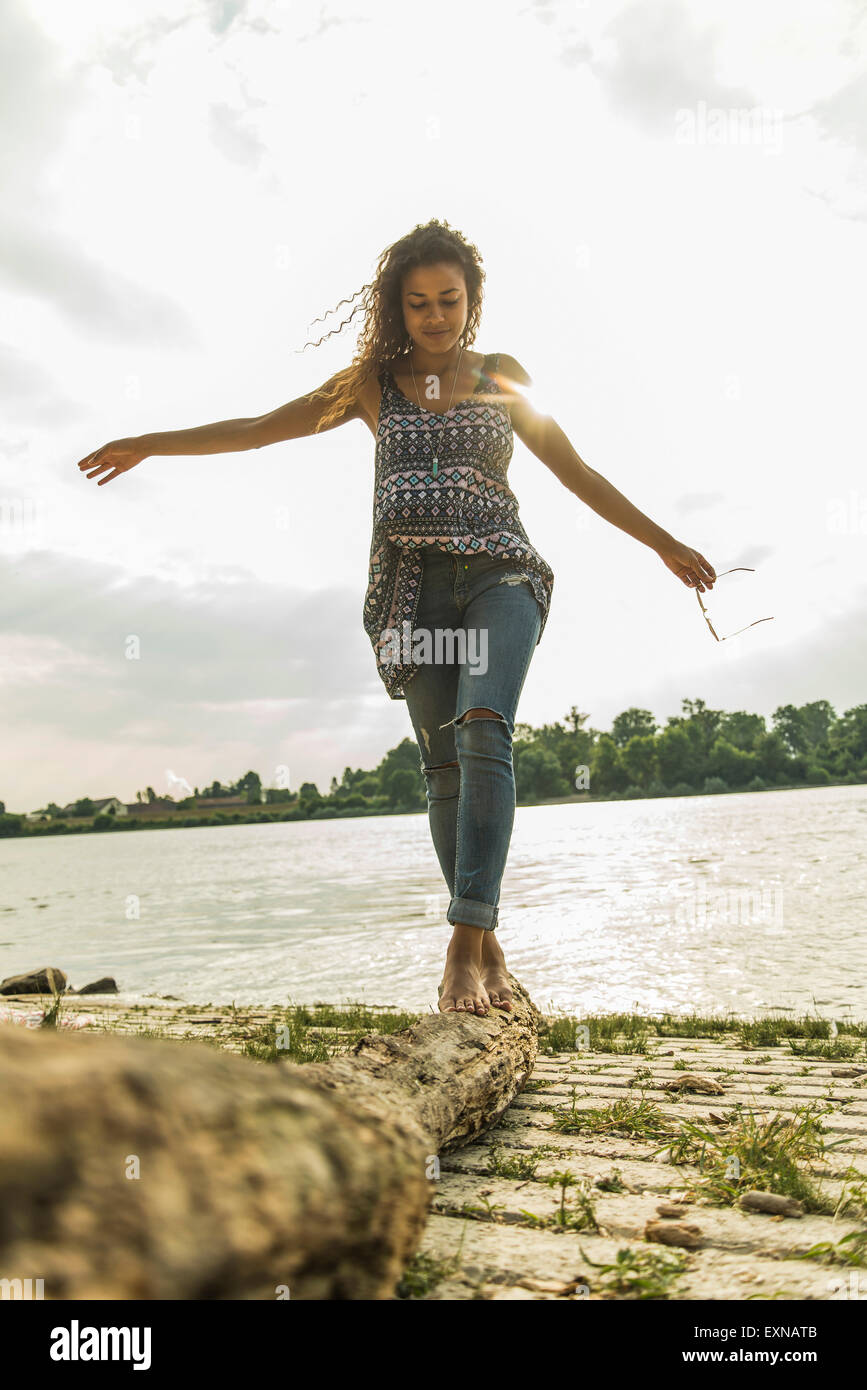 Young woman balancing on log by the riverside Stock Photo - Alamy