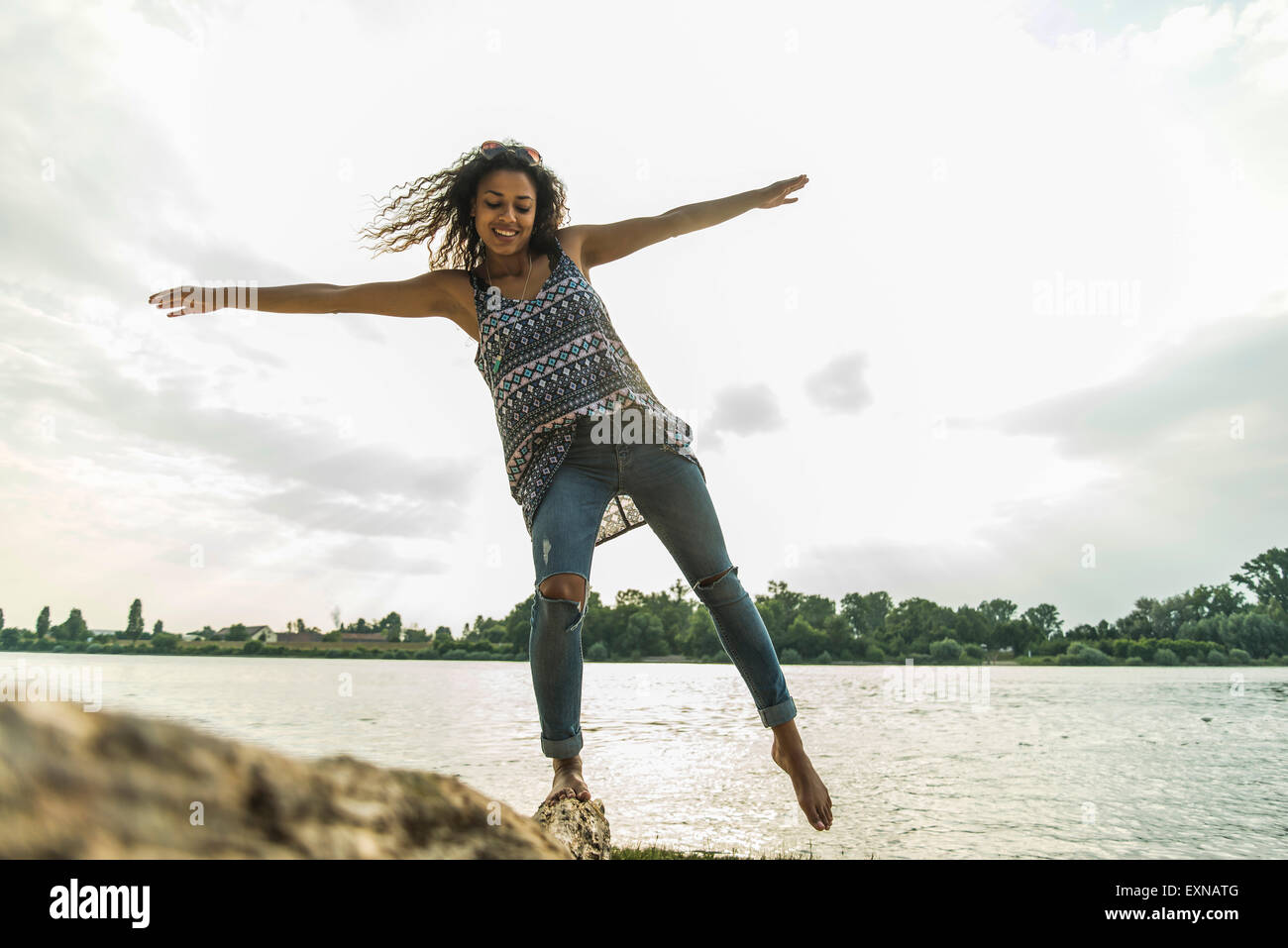 Young woman balancing on log by the riverside Stock Photo - Alamy