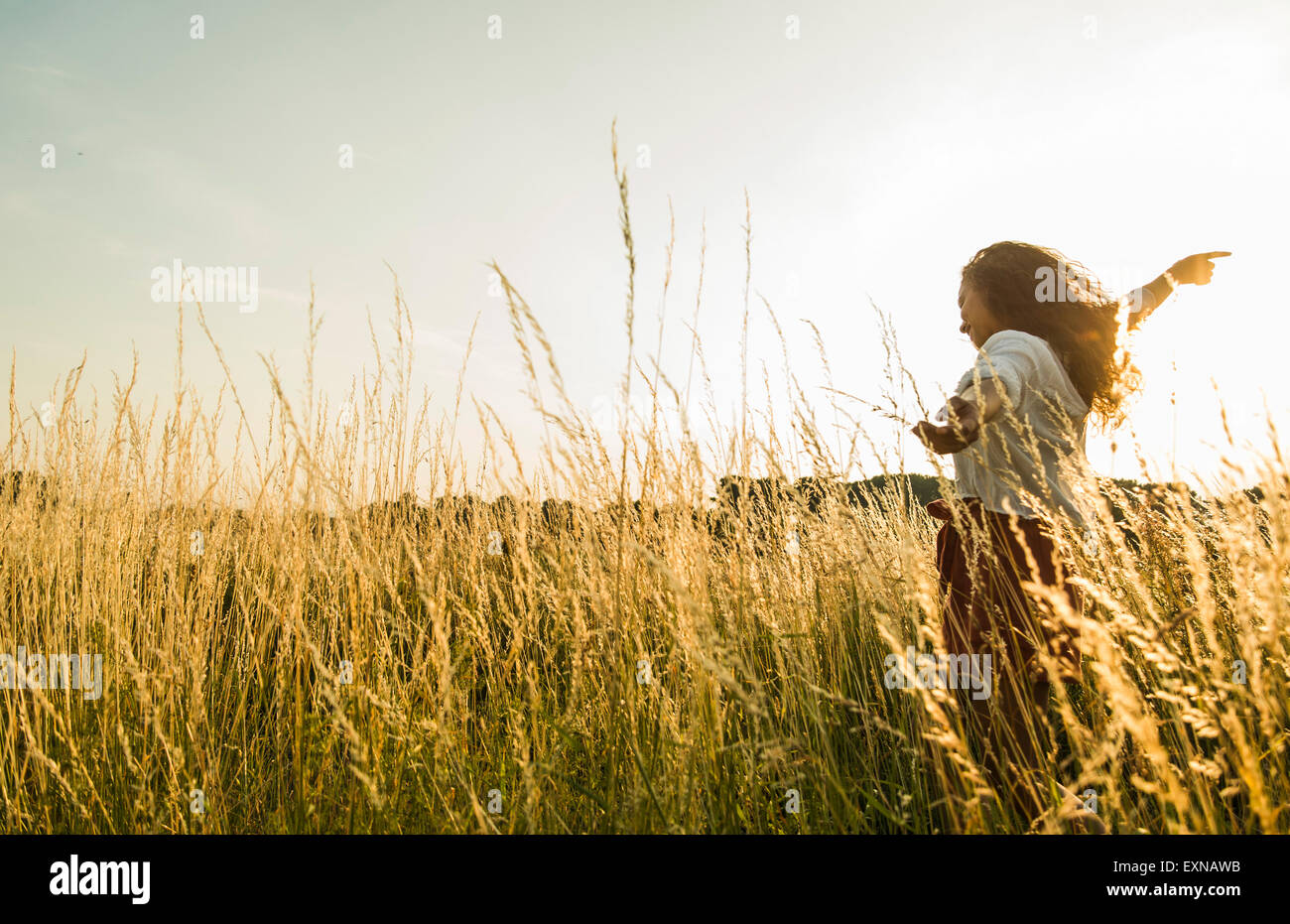 Young woman standing in field with tall grass Stock Photo - Alamy