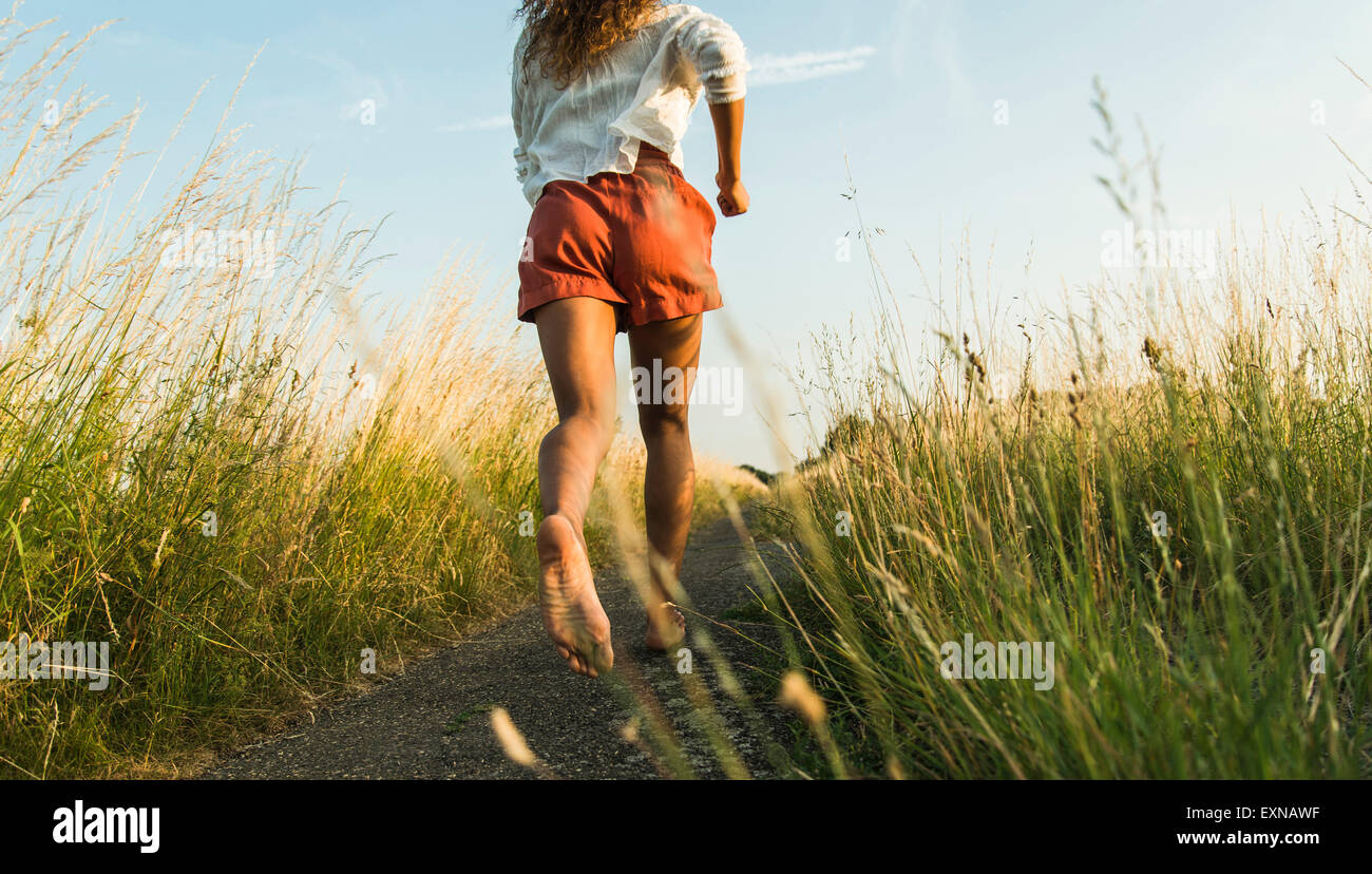 Young woman running on path in field Stock Photo - Alamy