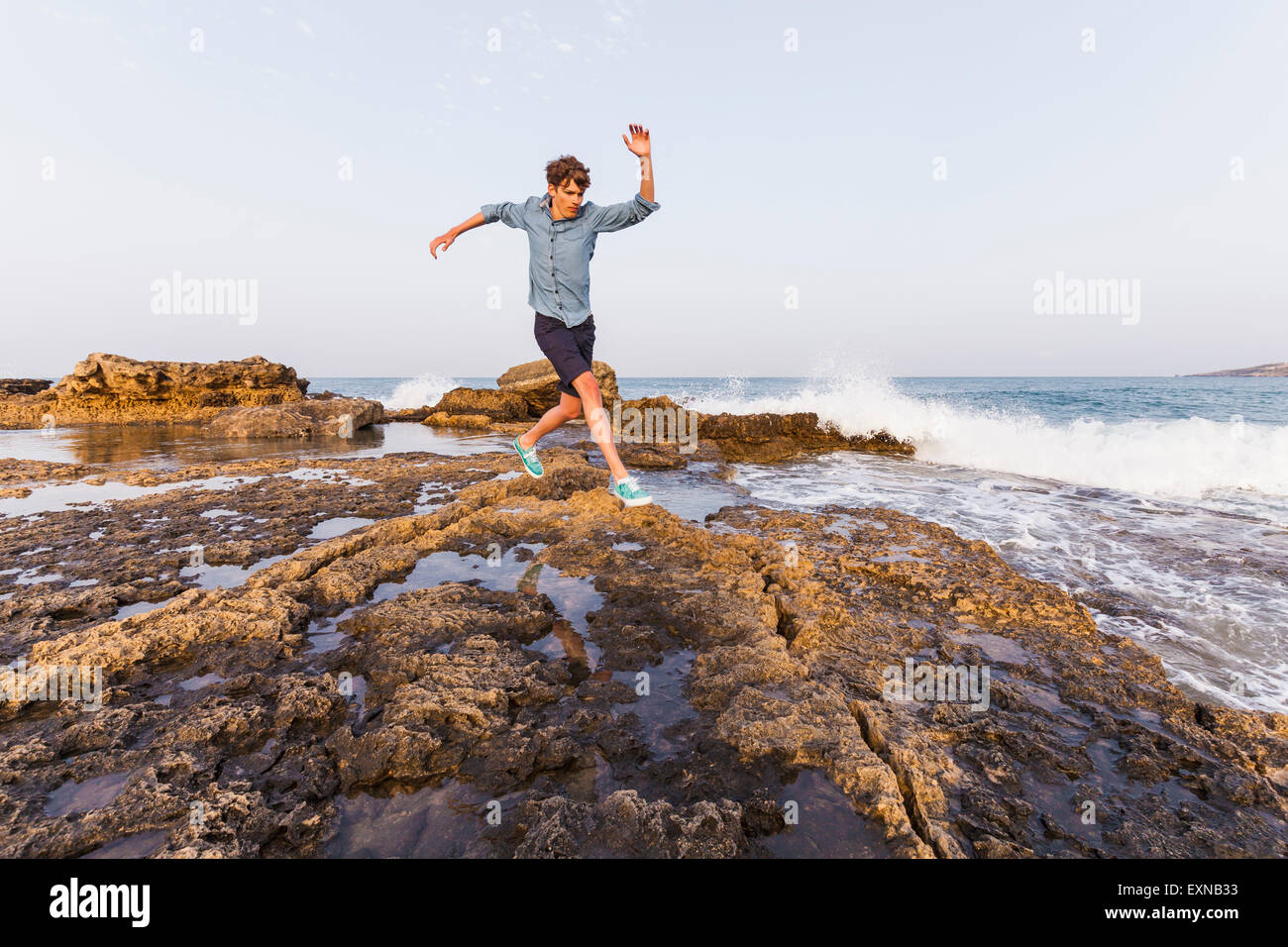 Greece, Rhodes, young man jumping on rocks at seafront Stock Photo - Alamy