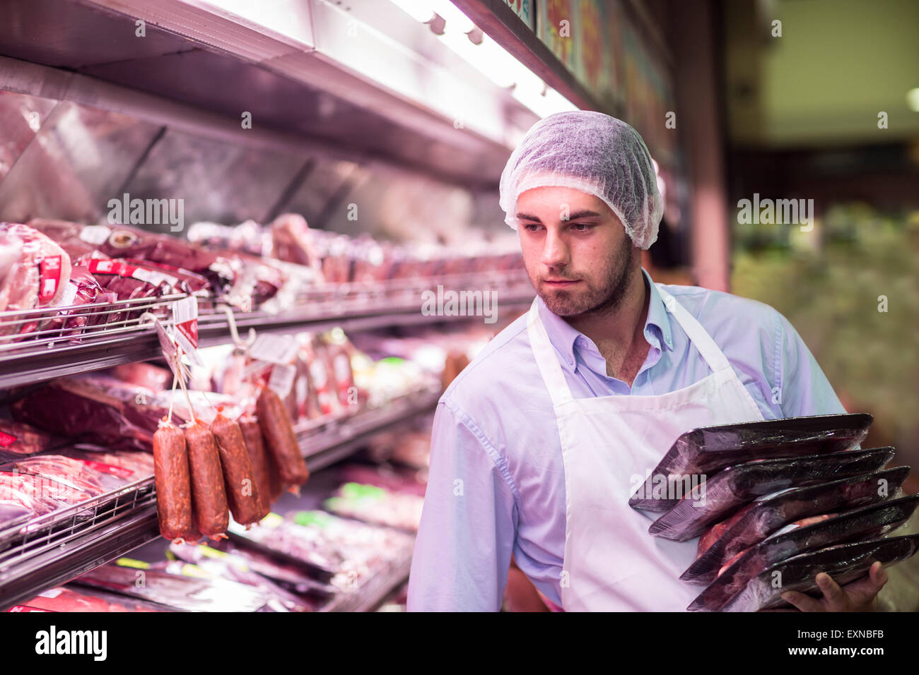 Butcher filling shelf with packaged meat Stock Photo - Alamy