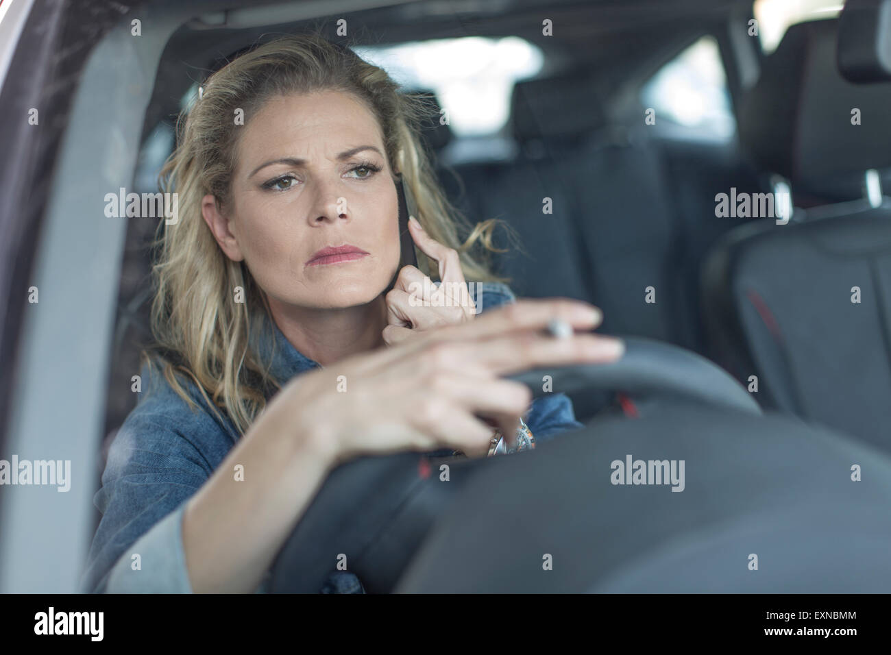 Serious woman in car on cell phone Stock Photo - Alamy