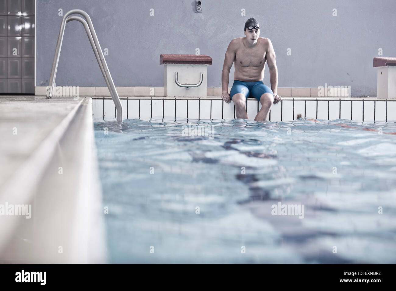 Swimmer in indoor pool sitting on pool edge Stock Photo - Alamy