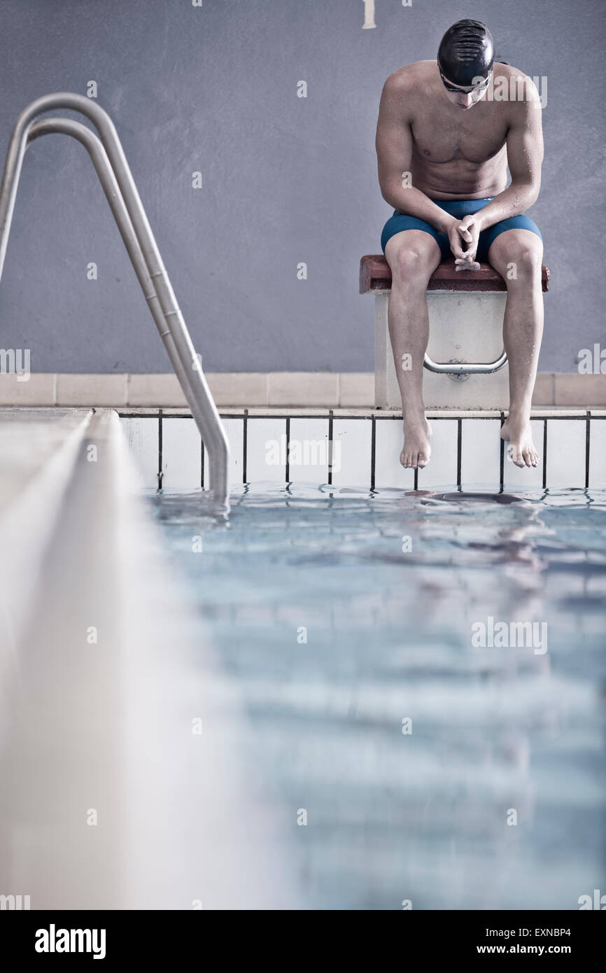 Swimmer in indoor pool sitting on starting block Stock Photo - Alamy