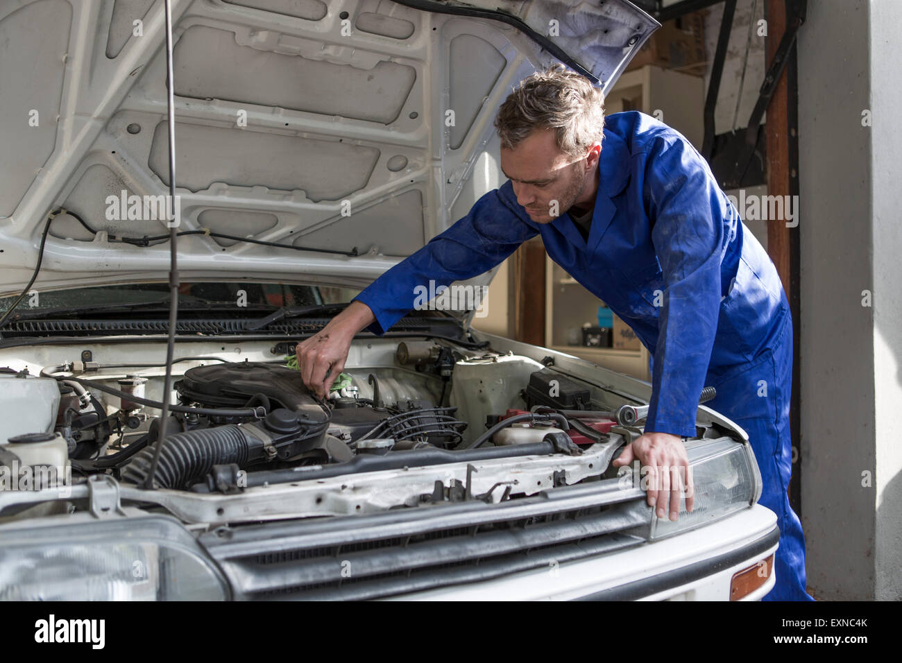 Man working on car in home garage Stock Photo - Alamy