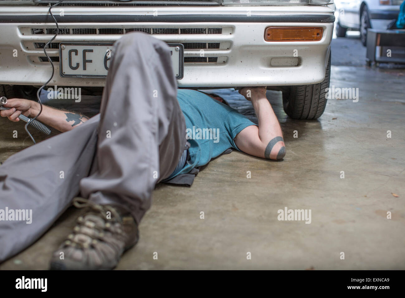 Mechanic lying working under car hi-res stock photography and images ...