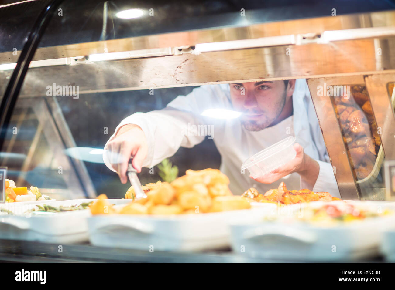 Shop assistant packing food from display at supermarket Stock Photo - Alamy