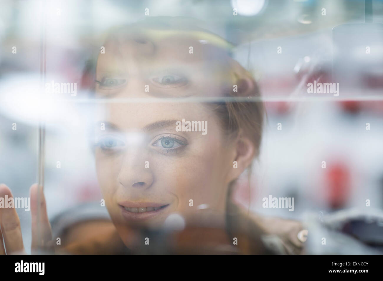 Young woman looking through shop window Stock Photo - Alamy