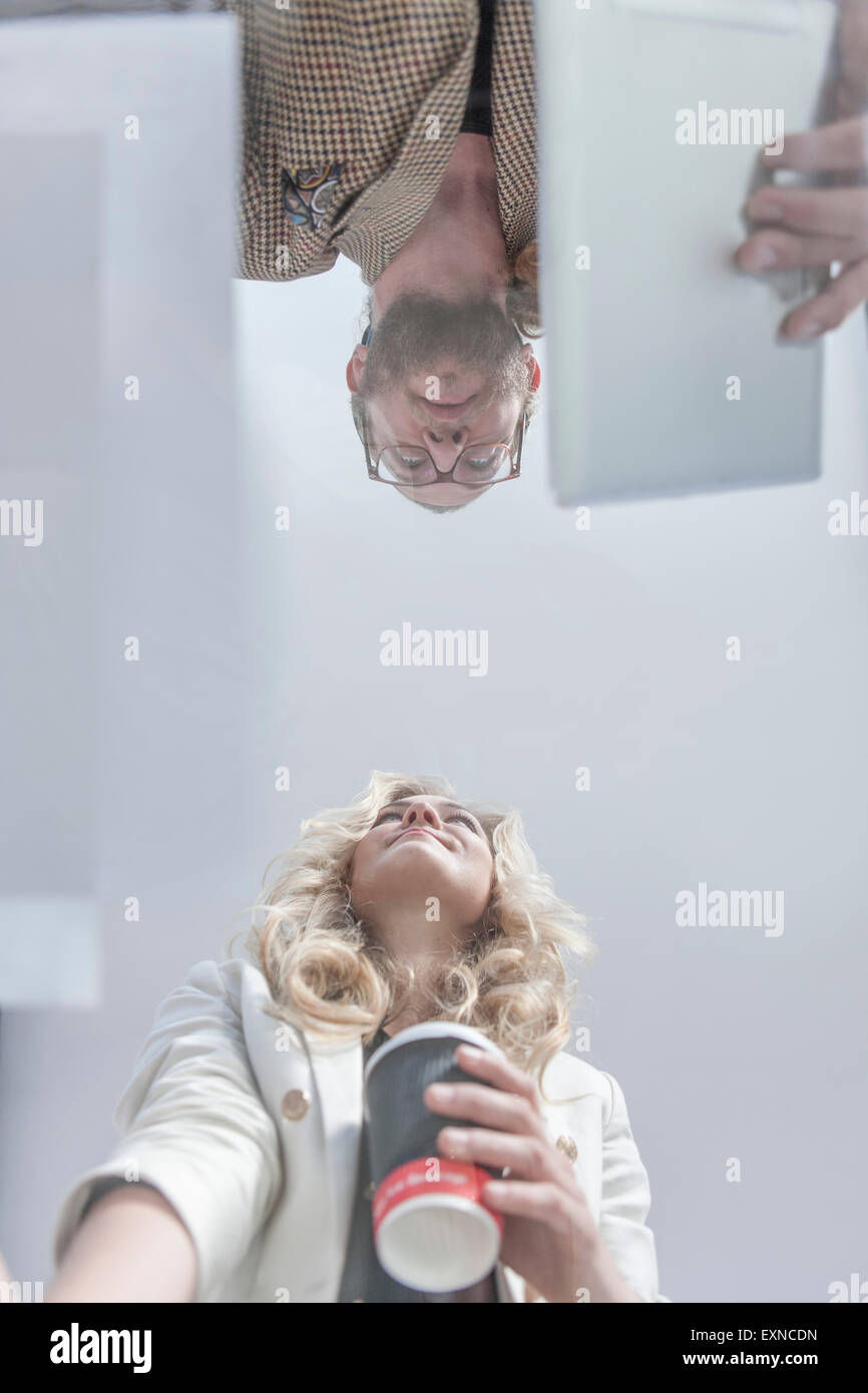 Two colleagues face to face leaning on glass table in an office Stock ...