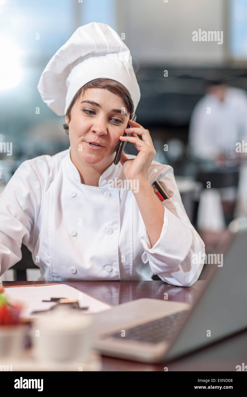 Restaurant chef sitting at table using mobile phone Stock Photo - Alamy