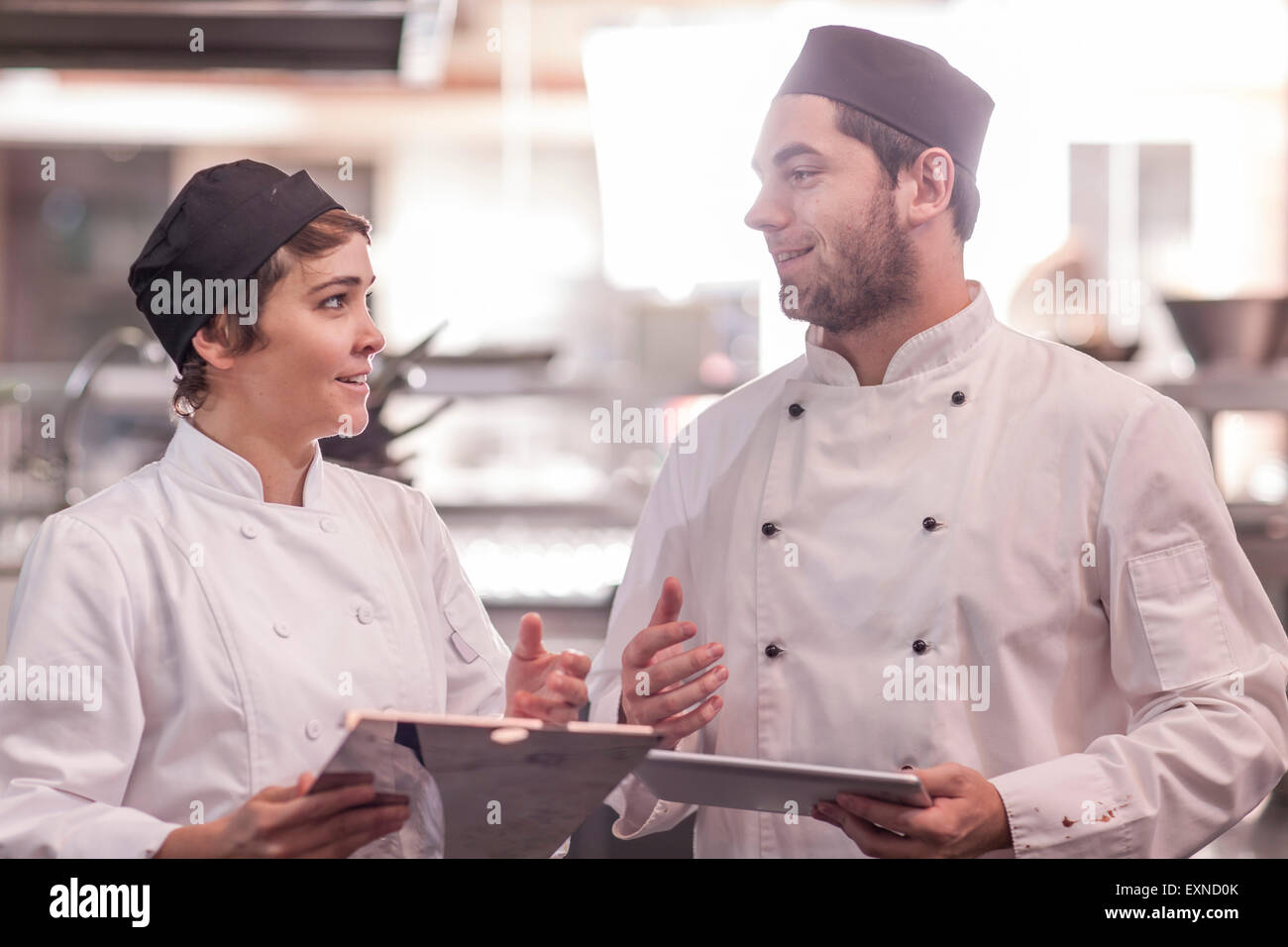 Two chefs working together in kitchen, using digital tablet Stock Photo ...
