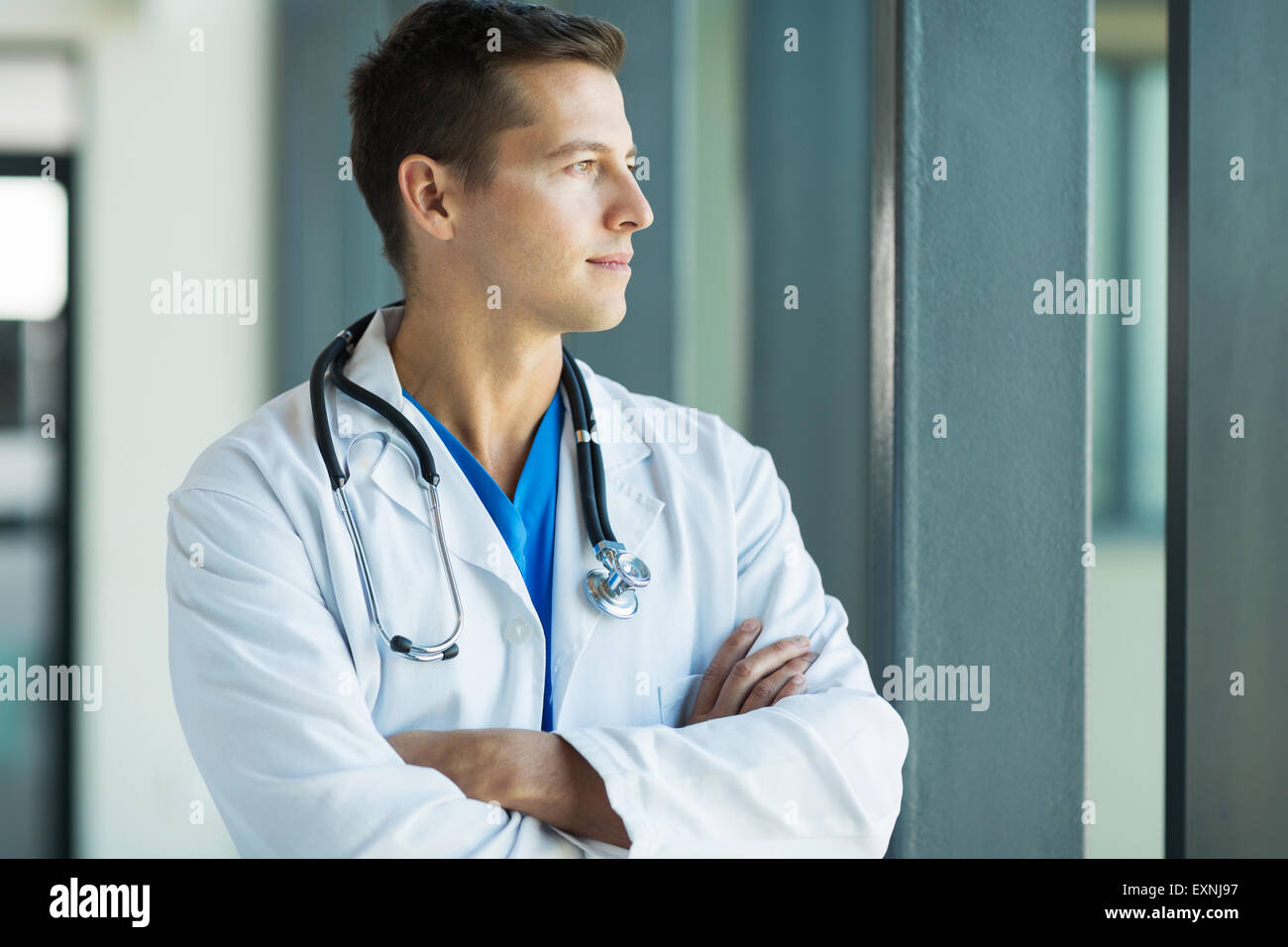 thoughtful young medical doctor with arms folded Stock Photo - Alamy