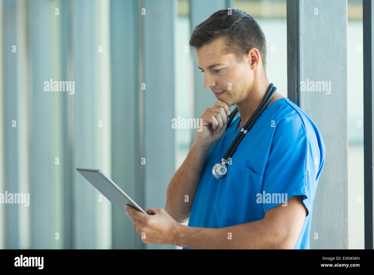 professional young medical intern using tablet computer at hospital ...